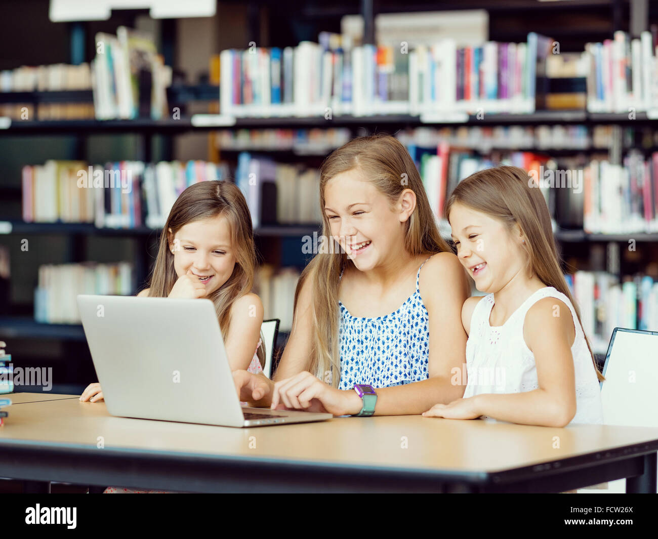 Little girls with a laptop in library Stock Photo - Alamy