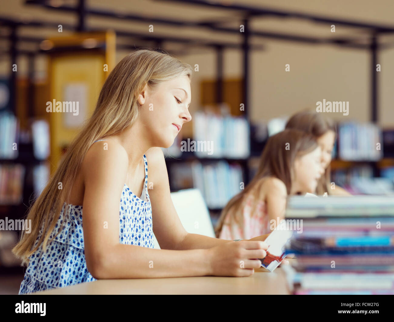 Little girls reading books in library Stock Photo - Alamy