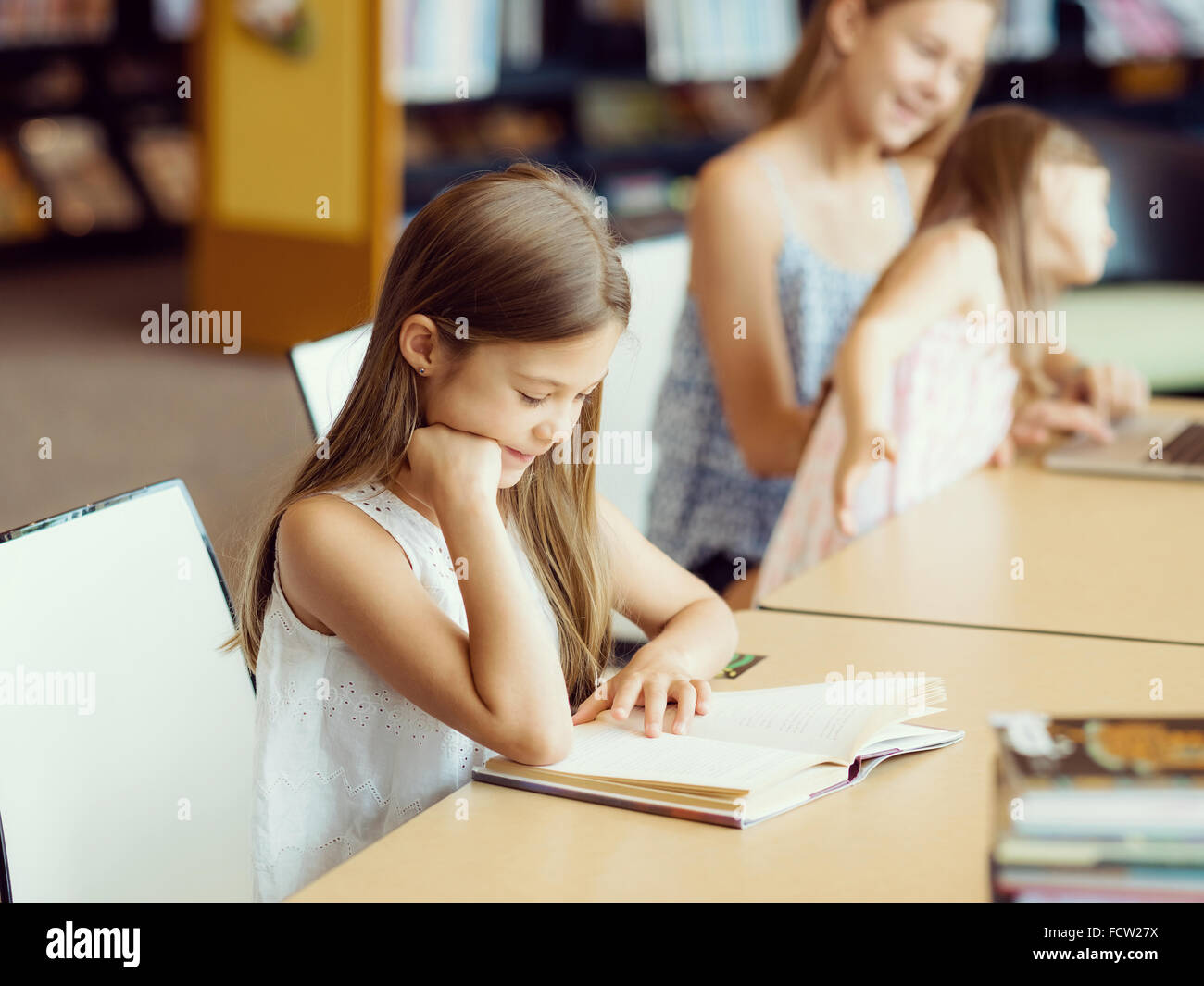 Little girls with a laptop in library Stock Photo - Alamy