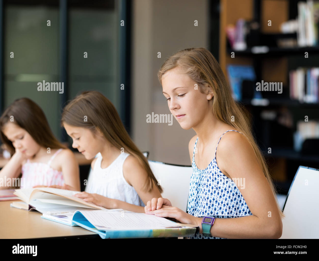 Little girls reading books in library Stock Photo - Alamy
