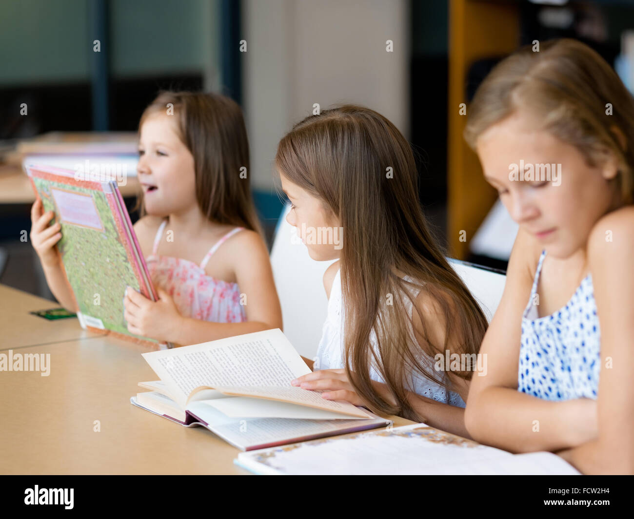 Little girls reading books in library Stock Photo - Alamy