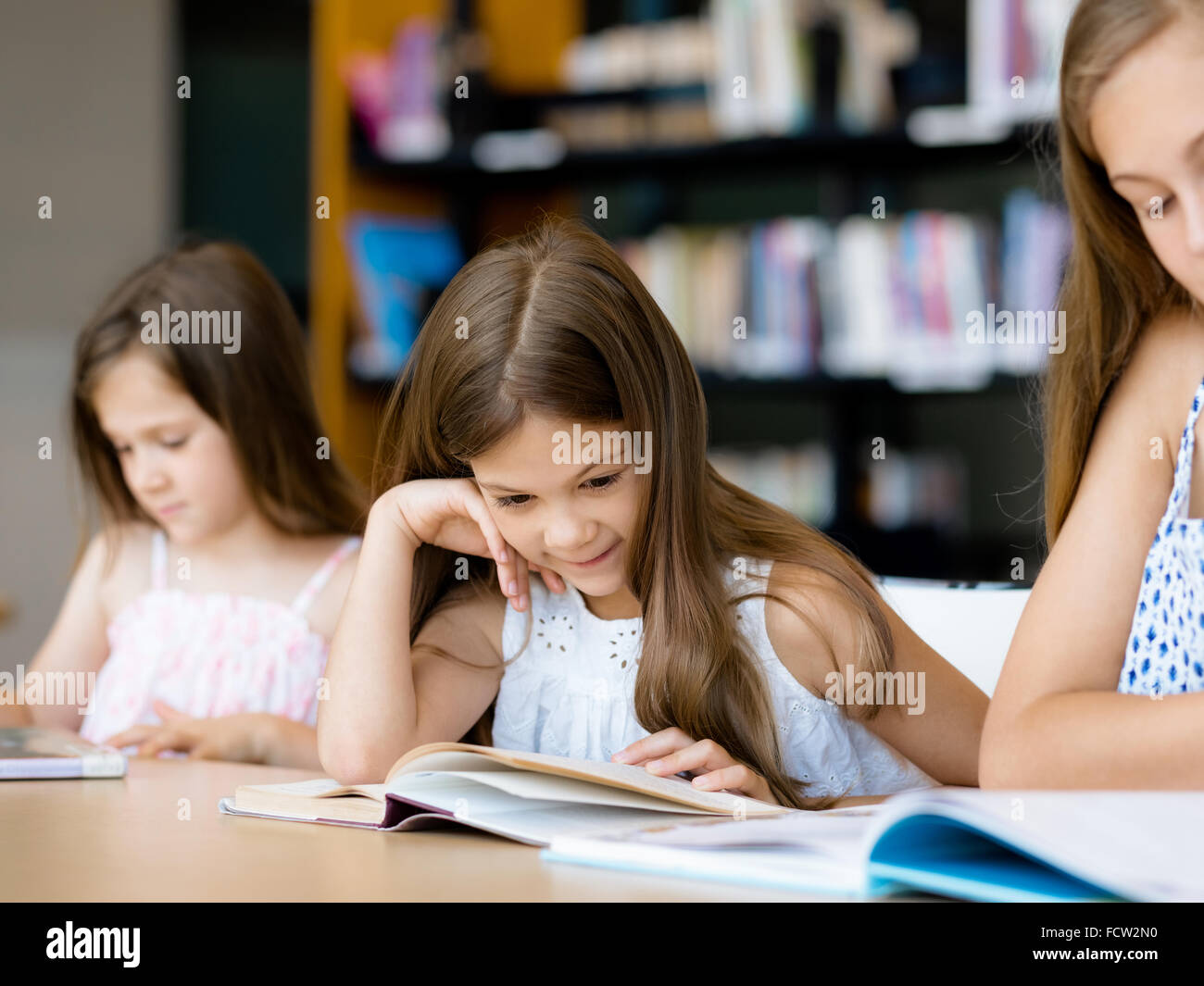 Little girls reading books in library Stock Photo - Alamy
