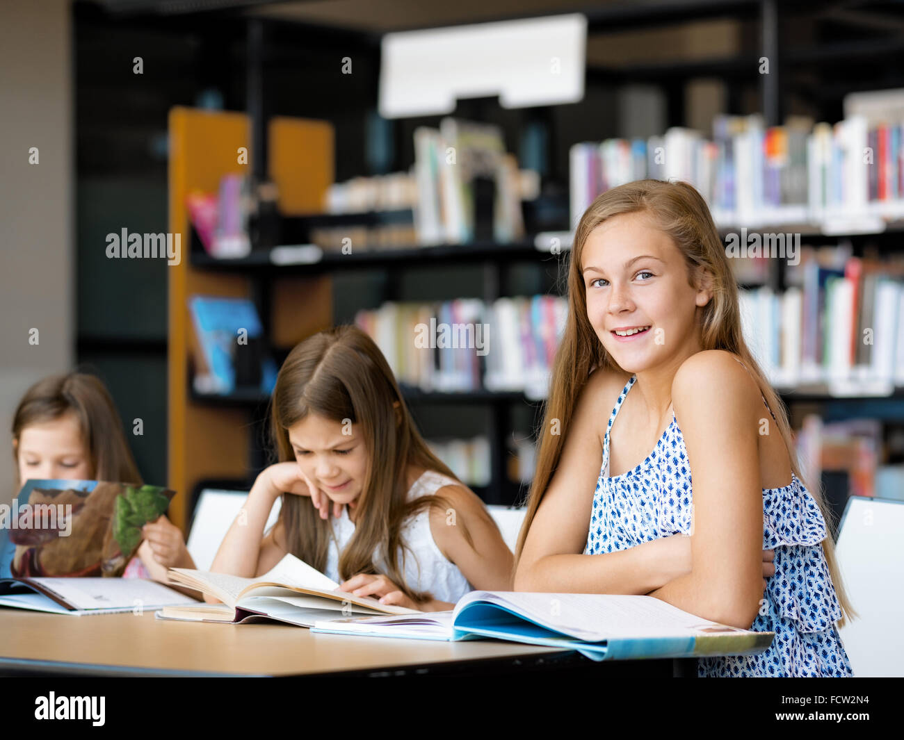Little girls reading books in library Stock Photo - Alamy