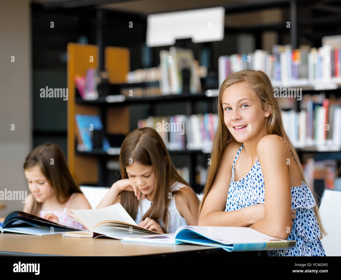Little girls reading books in library Stock Photo - Alamy