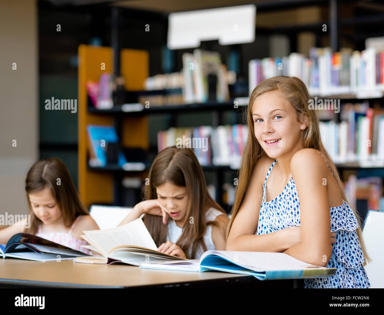 Little girls reading books in library Stock Photo - Alamy