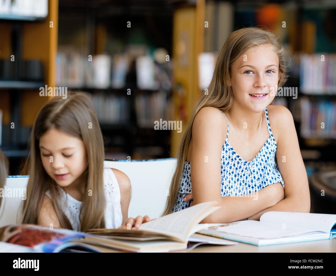 Little girls reading books in library Stock Photo - Alamy