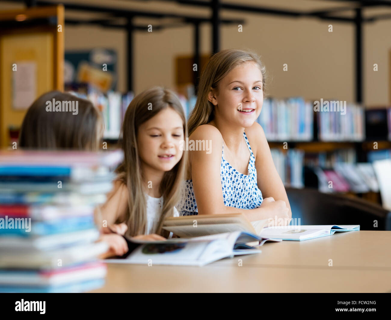 Little girls reading books in library Stock Photo - Alamy