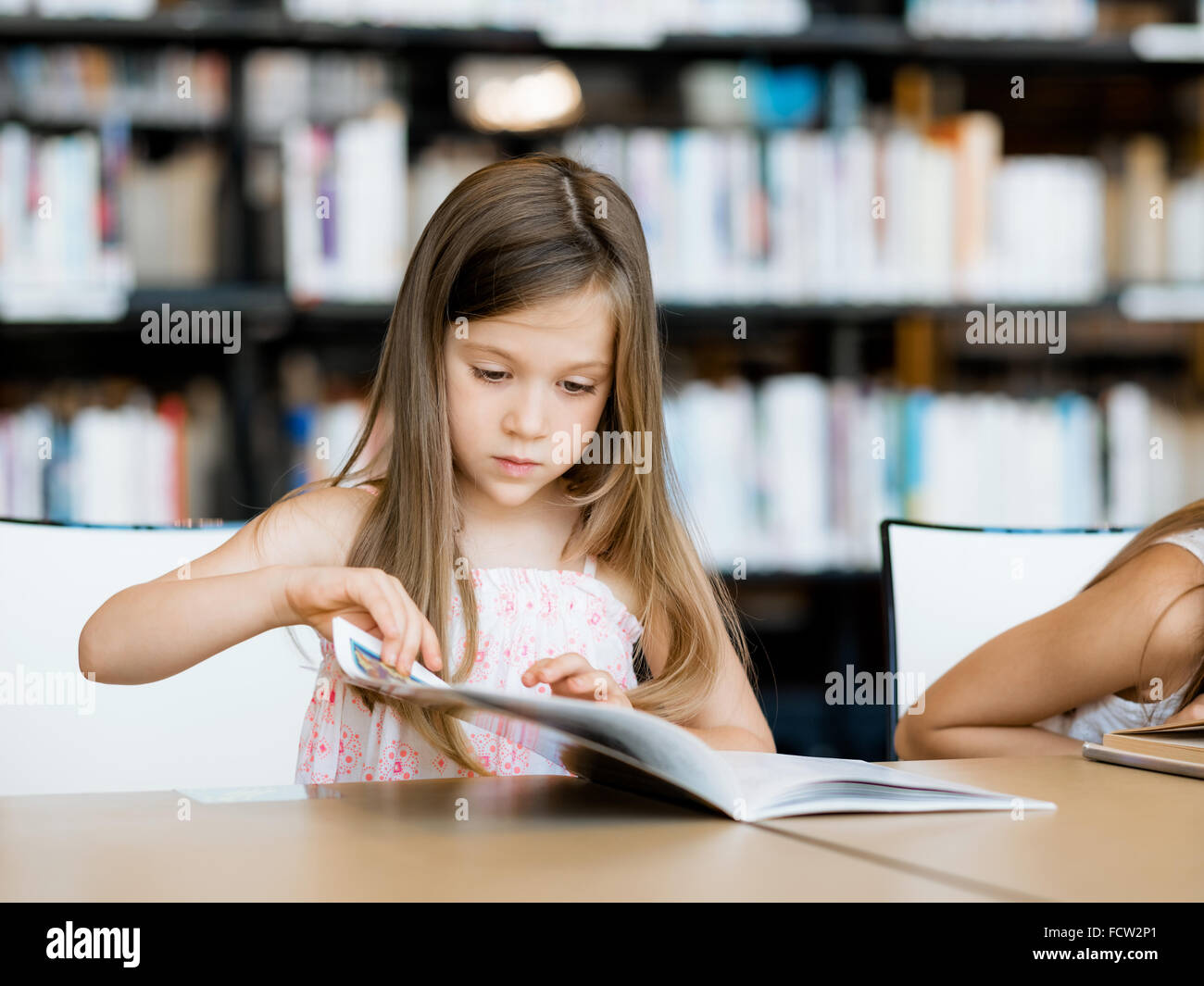 Little girl reading books in library Stock Photo - Alamy
