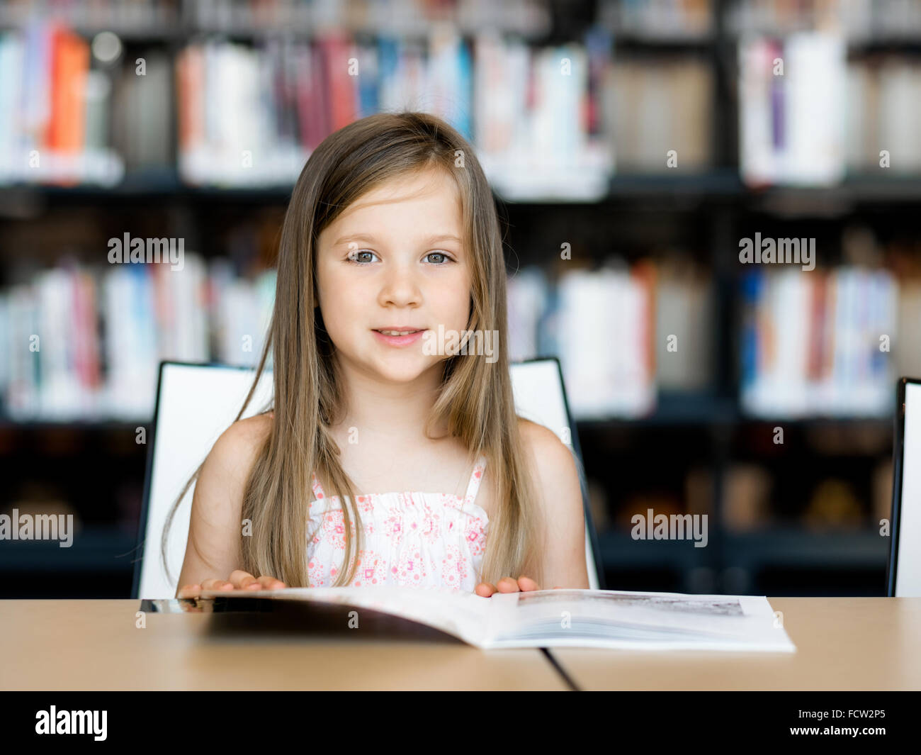 Little girl reading books in library Stock Photo - Alamy