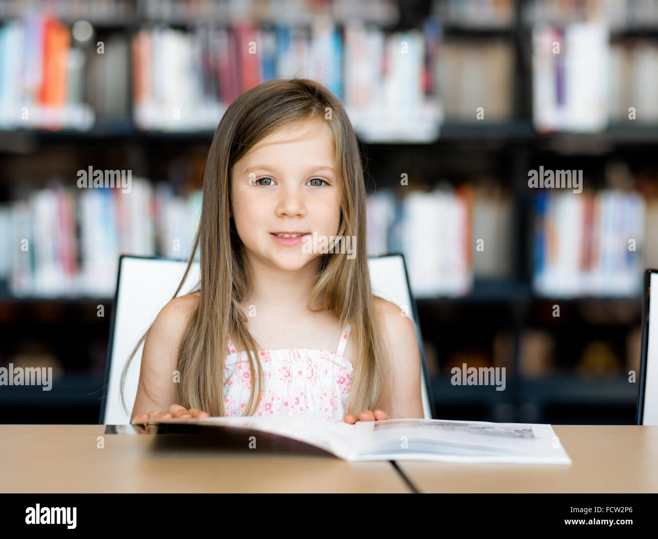 Little girl reading books in library Stock Photo - Alamy