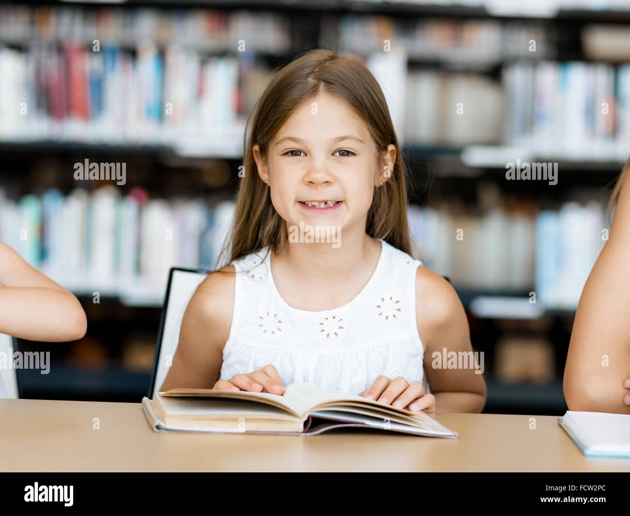 Little girl reading books in library Stock Photo - Alamy
