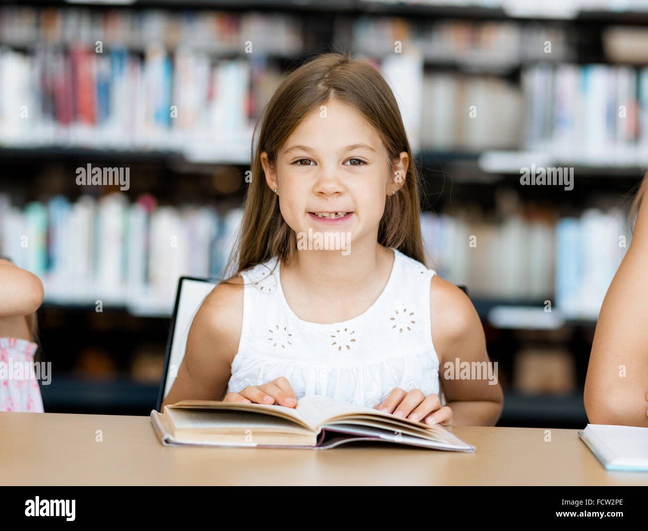 Little girl reading books in library Stock Photo - Alamy