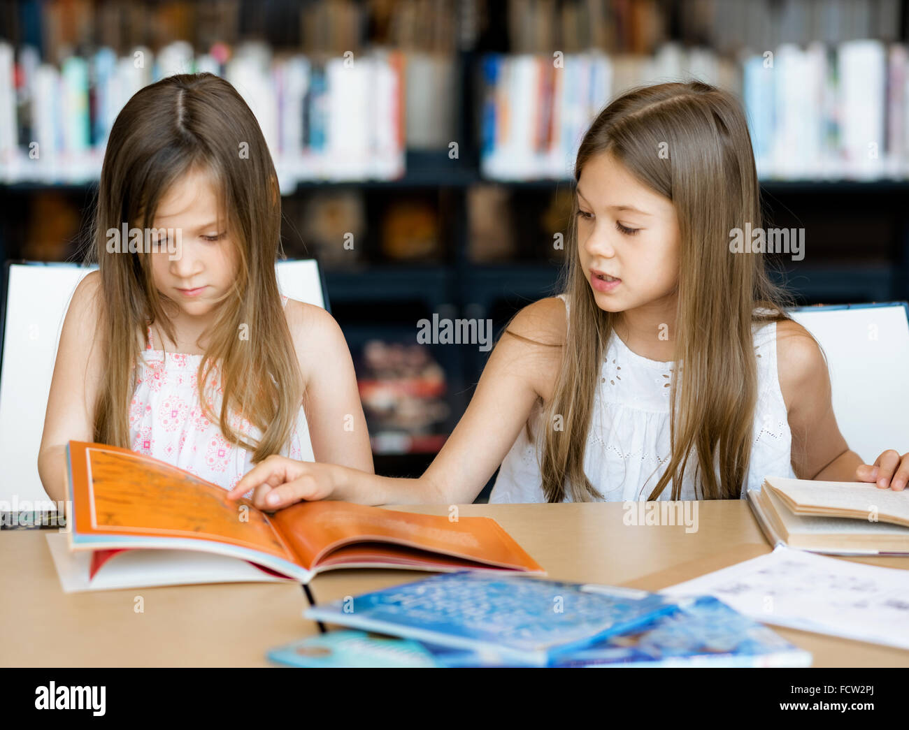 Little girls reading books in library Stock Photo - Alamy