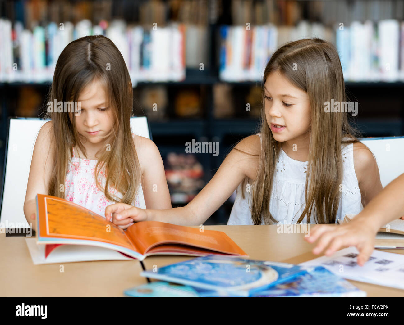 Little girls reading books in library Stock Photo - Alamy