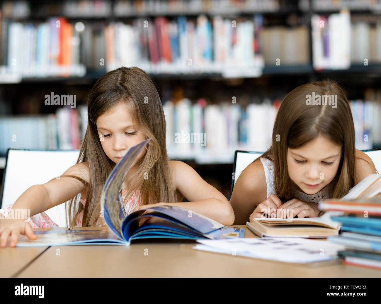Little girls reading books in library Stock Photo - Alamy