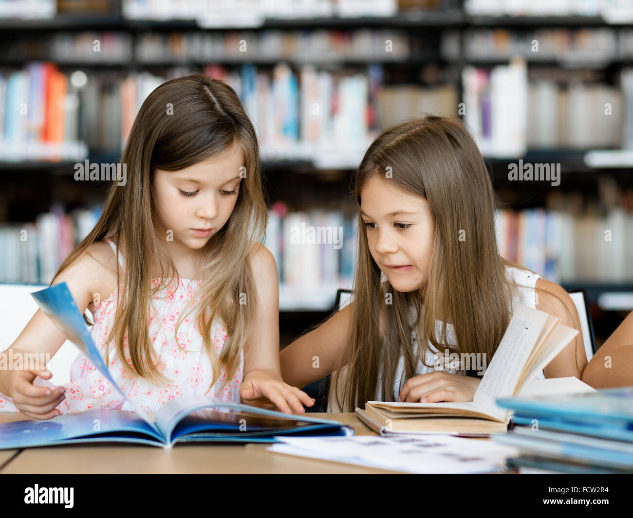 Little girls reading books in library Stock Photo - Alamy