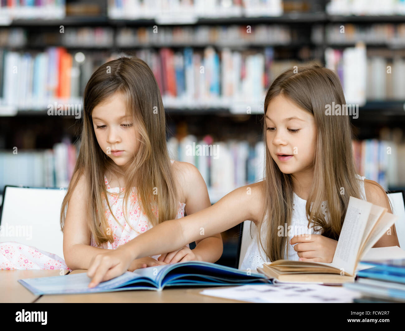 Little girls reading books in library Stock Photo - Alamy