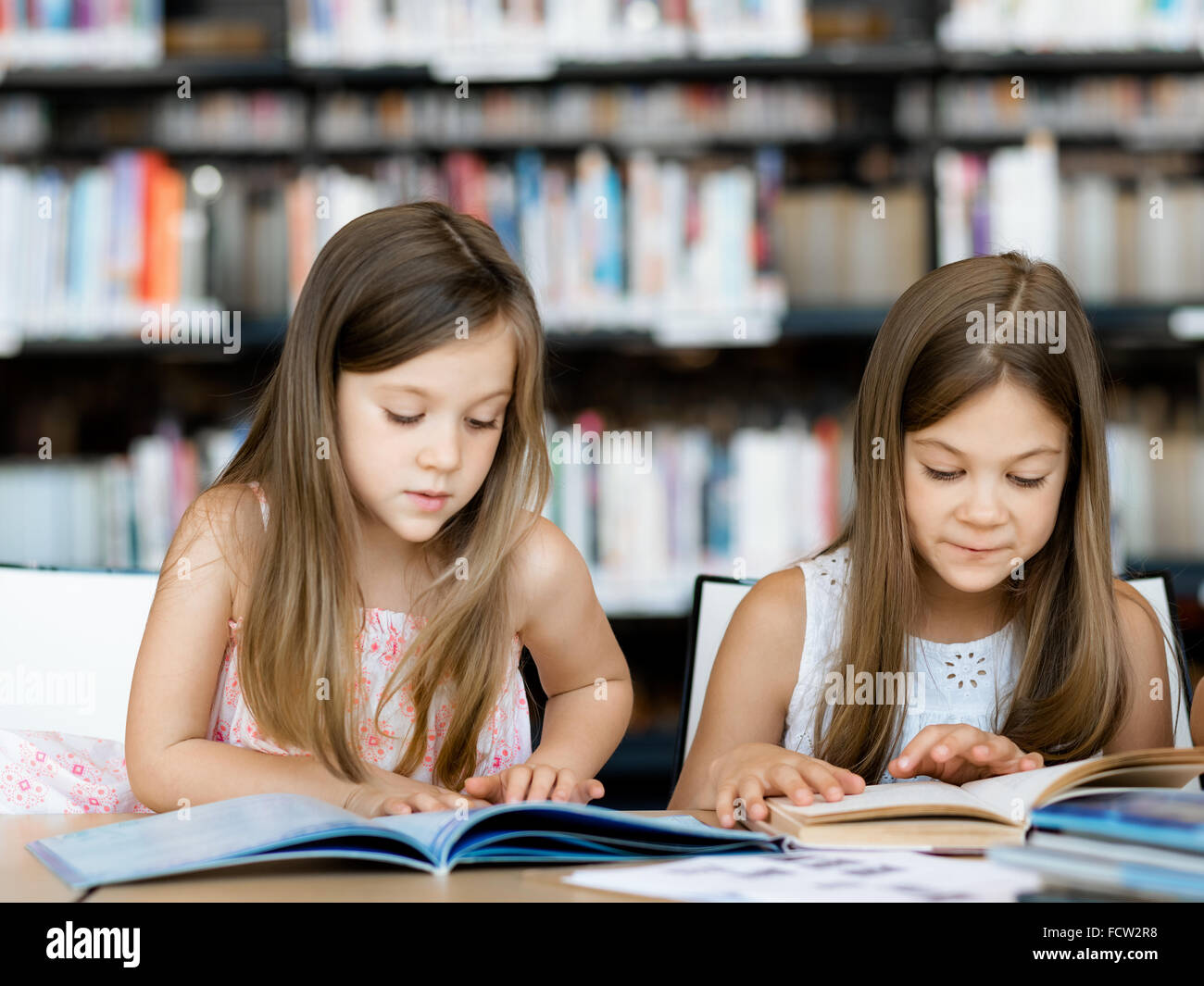 Little girls reading books in library Stock Photo - Alamy