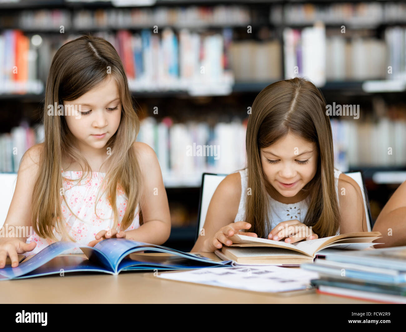 Little girls reading books in library Stock Photo - Alamy