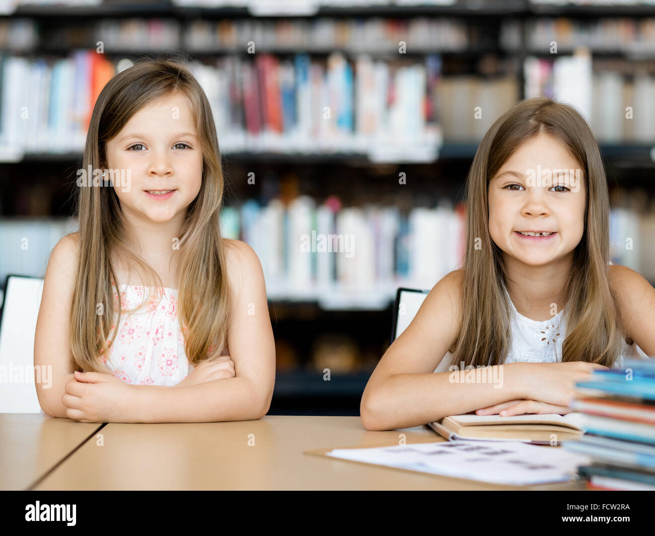 Little girls reading books in library Stock Photo - Alamy