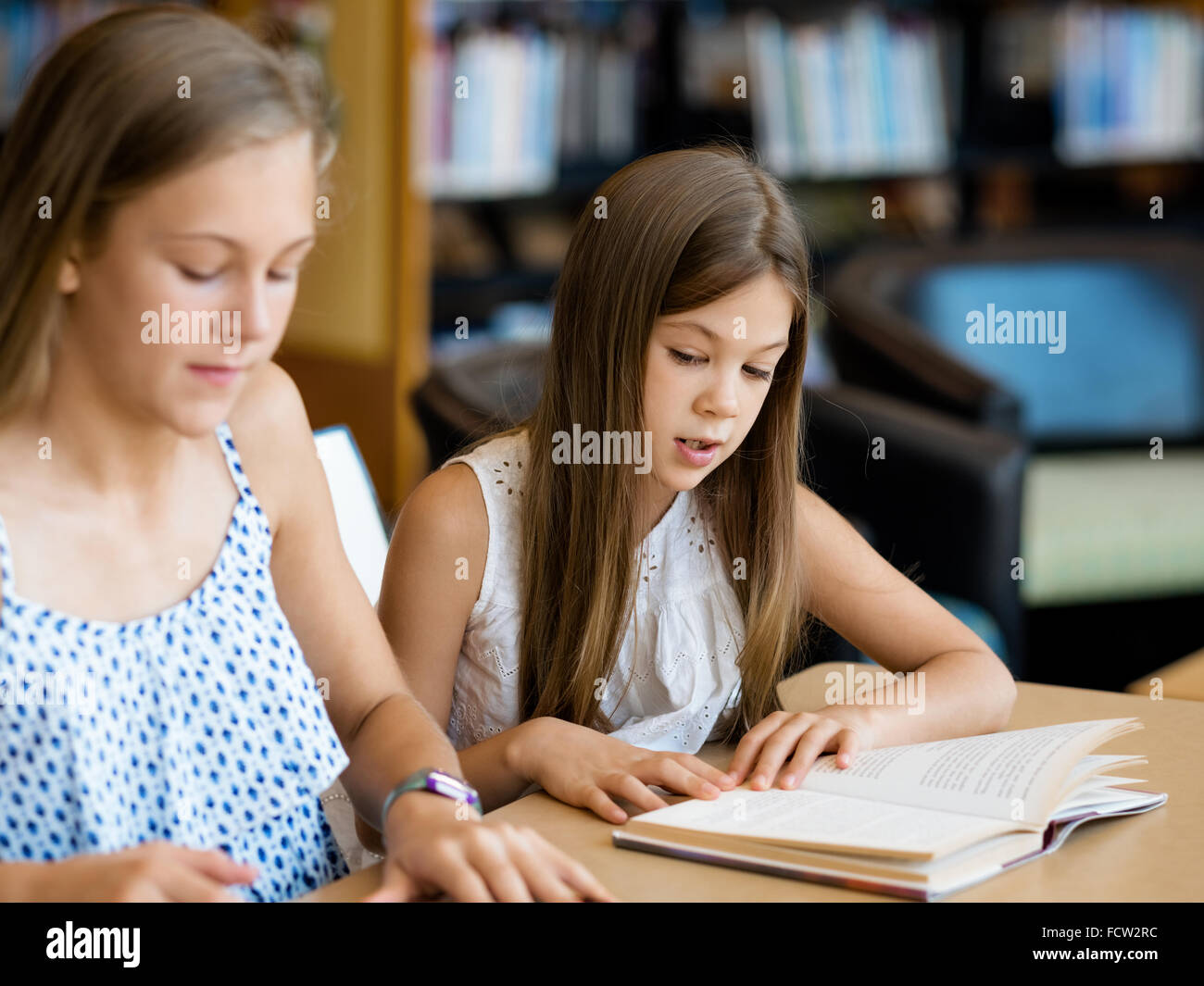 Little girls reading books in library Stock Photo - Alamy