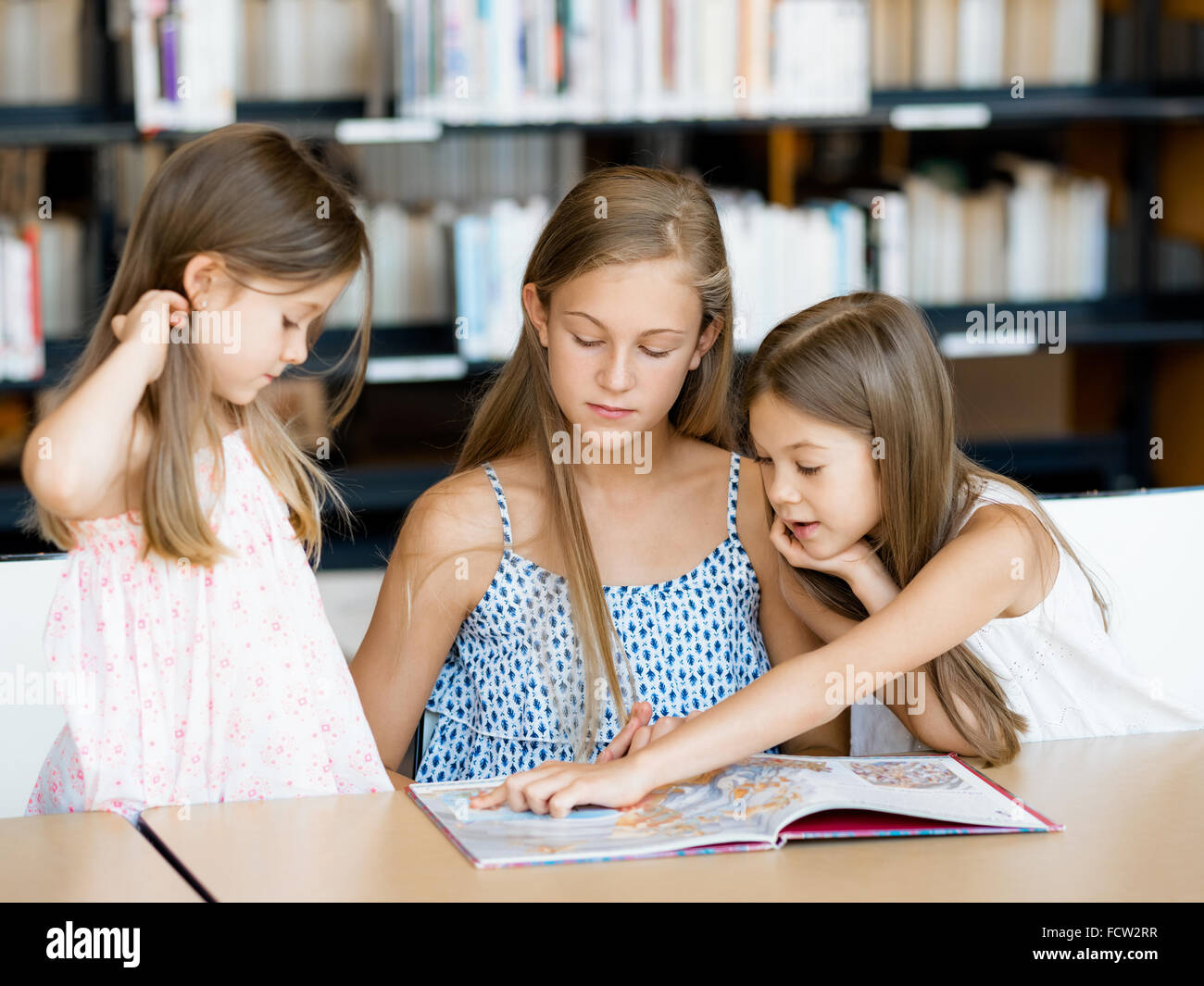Little girls reading books in library Stock Photo - Alamy