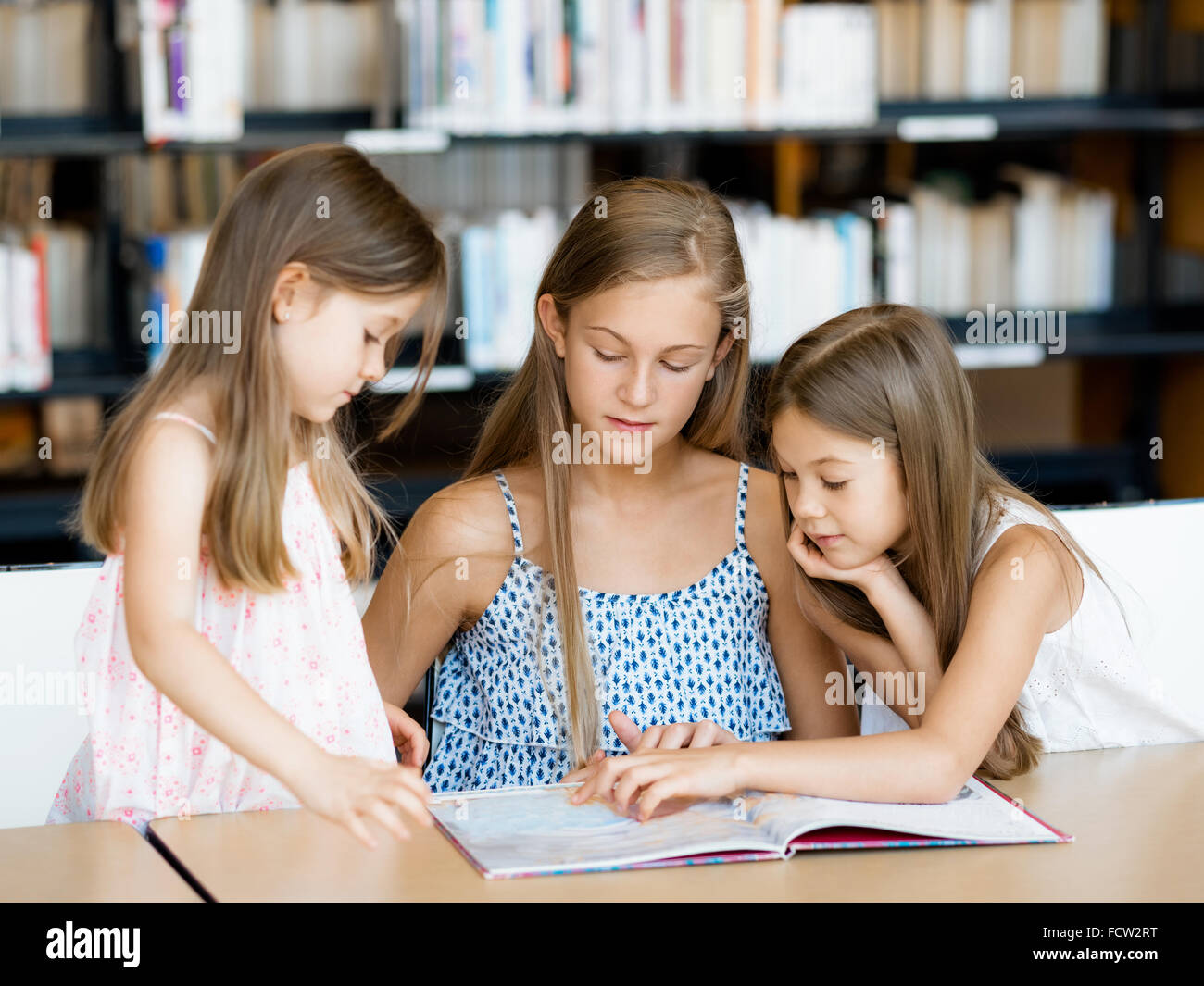 Little girls reading books in library Stock Photo - Alamy