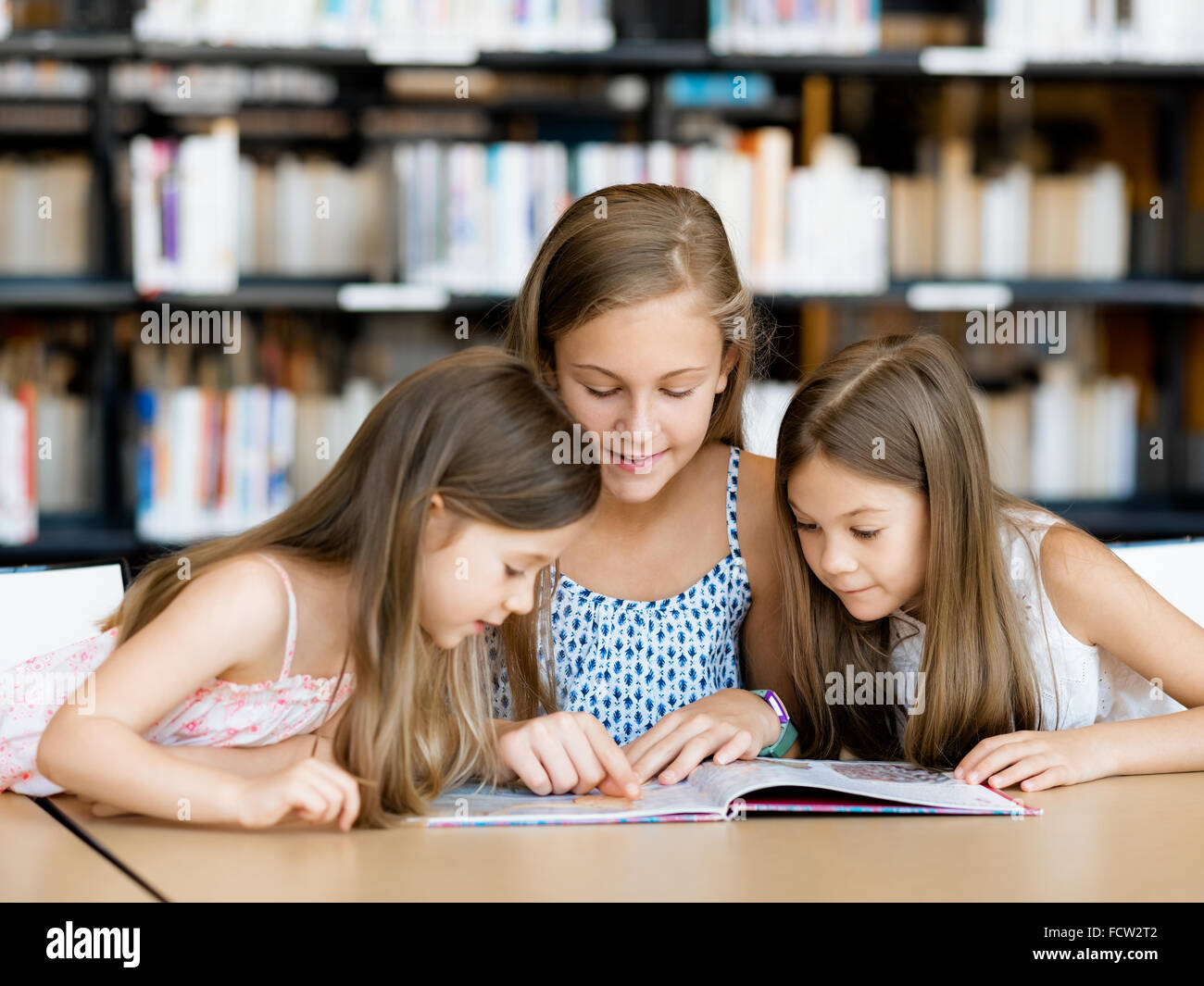 Little girls reading books in library Stock Photo - Alamy