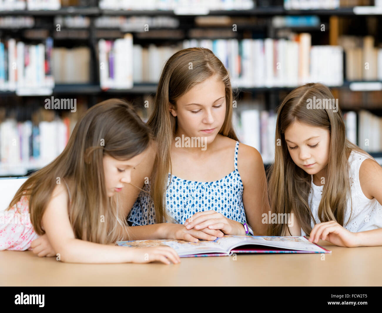 Little girls reading books in library Stock Photo - Alamy