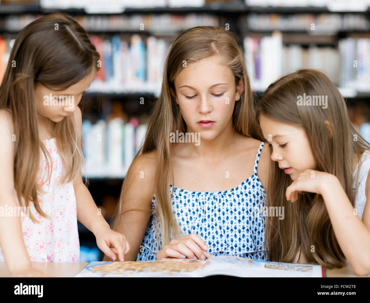 Little girls reading books in library Stock Photo - Alamy