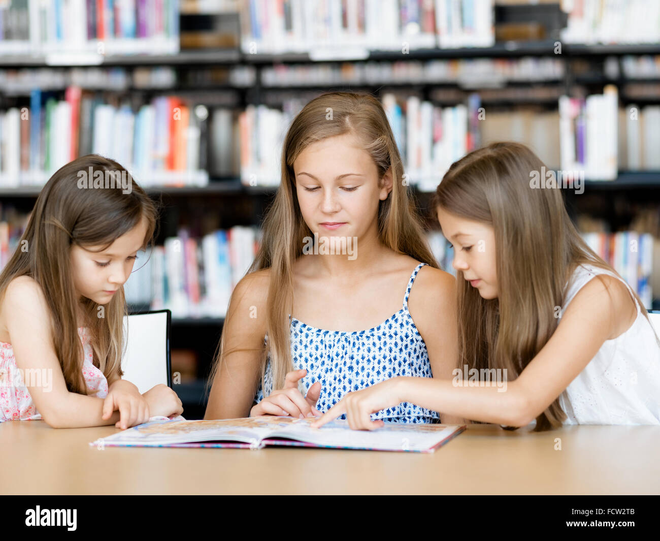 Little girls reading books in library Stock Photo - Alamy