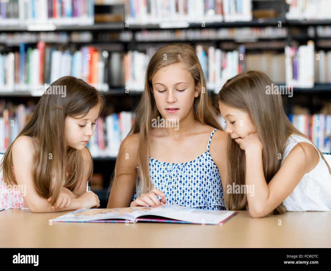 Little girls reading books in library Stock Photo - Alamy