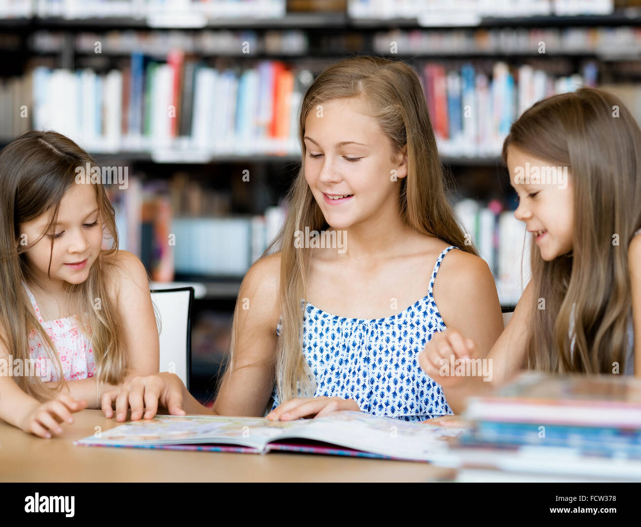 Little girls reading books in library Stock Photo - Alamy