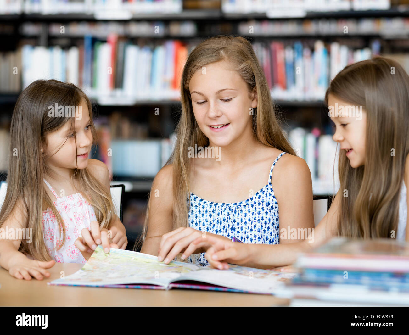 Little girls reading books in library Stock Photo - Alamy