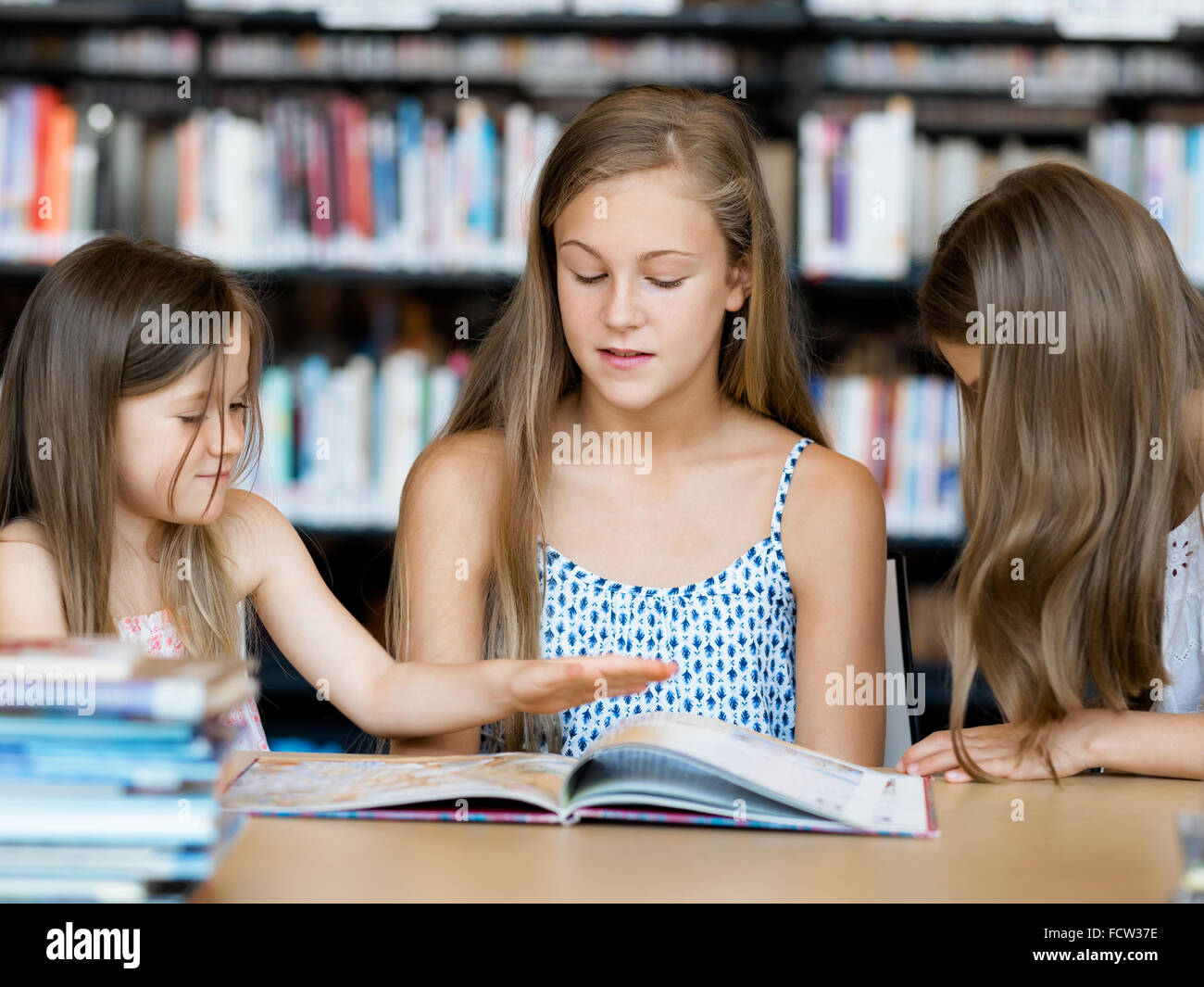 Little girls reading books in library Stock Photo - Alamy
