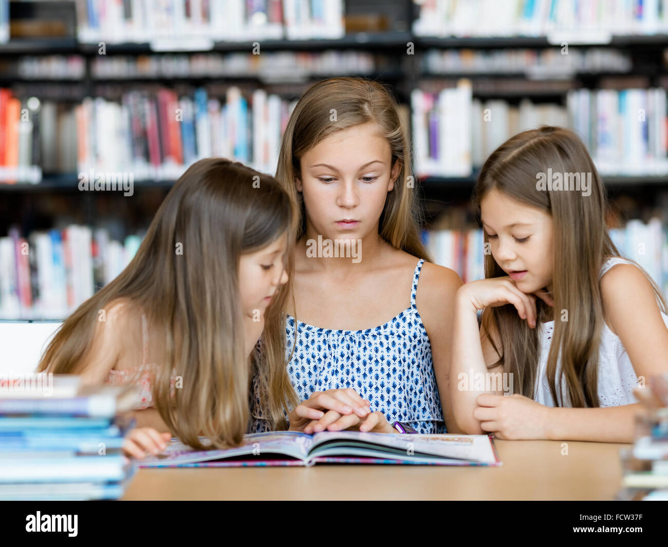 Little girls reading books in library Stock Photo - Alamy