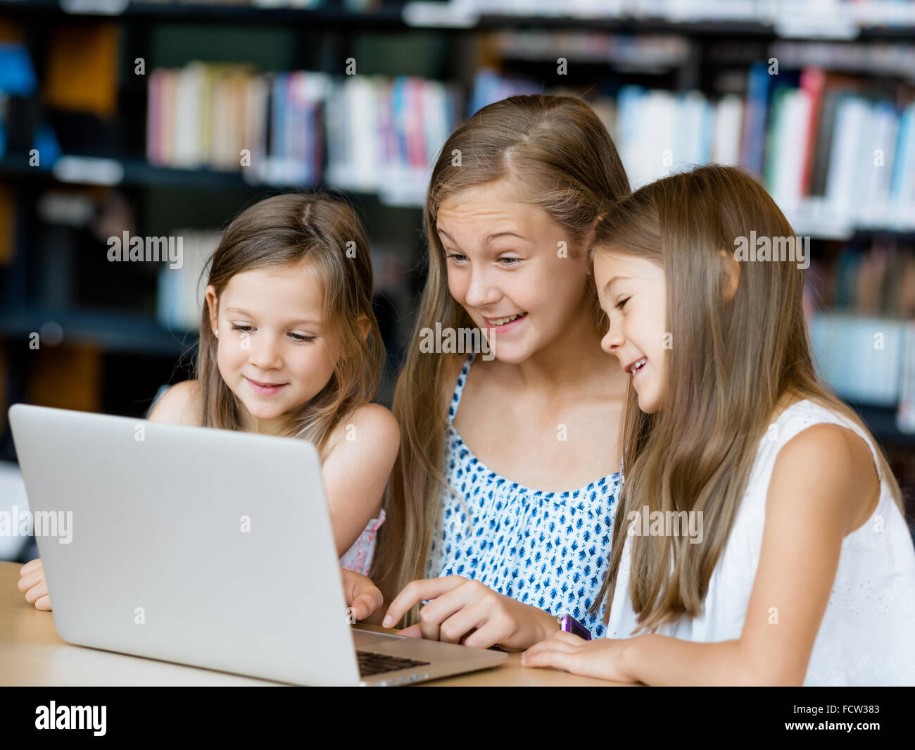 Little girls with a laptop in library Stock Photo - Alamy