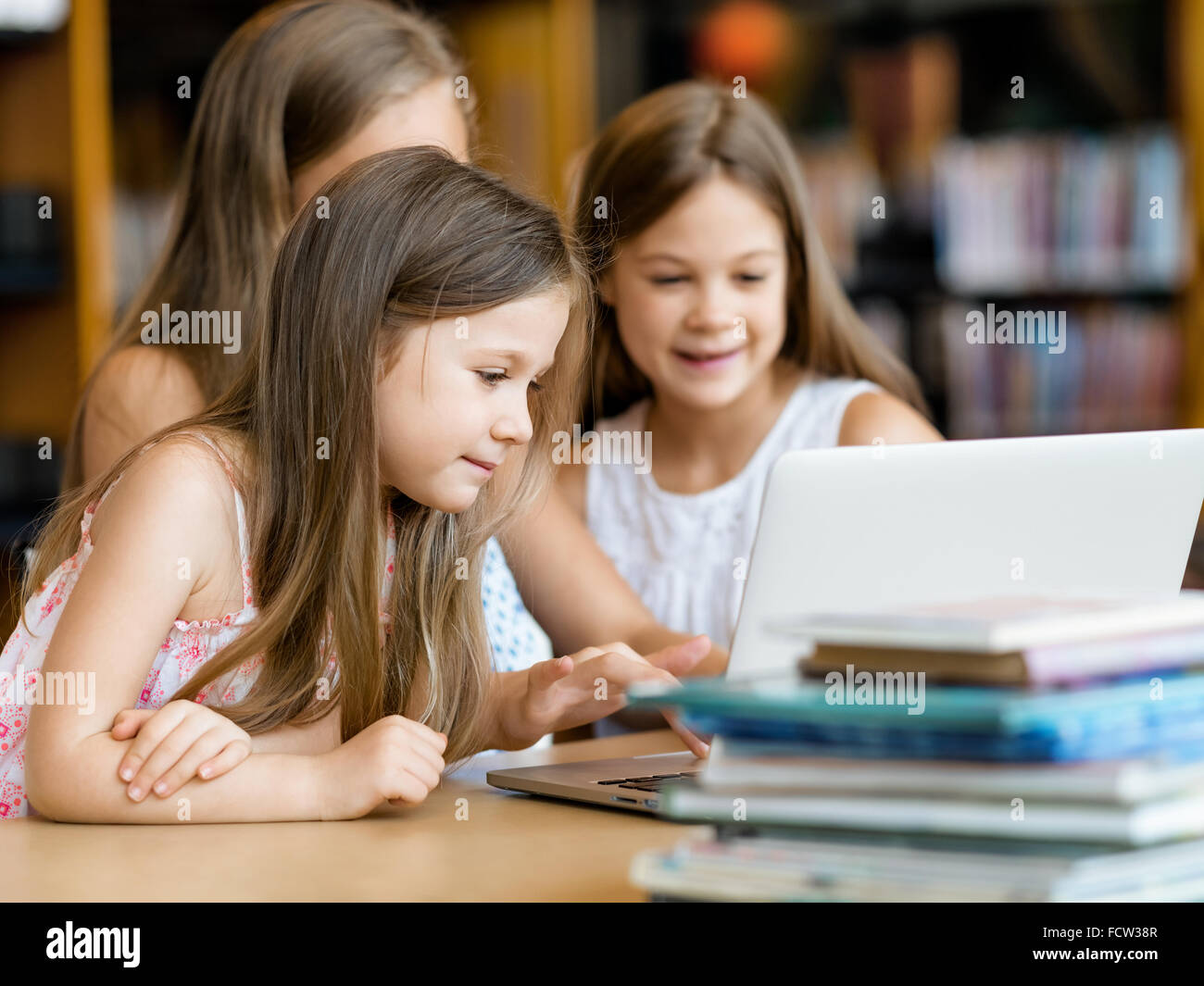 Little girls with a laptop in library Stock Photo - Alamy