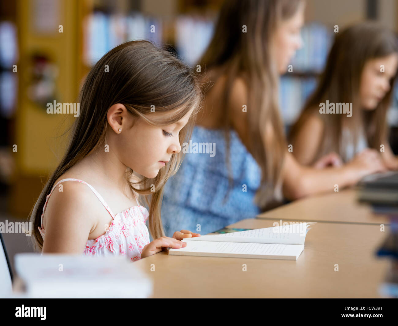 Little girls reading books in library Stock Photo - Alamy