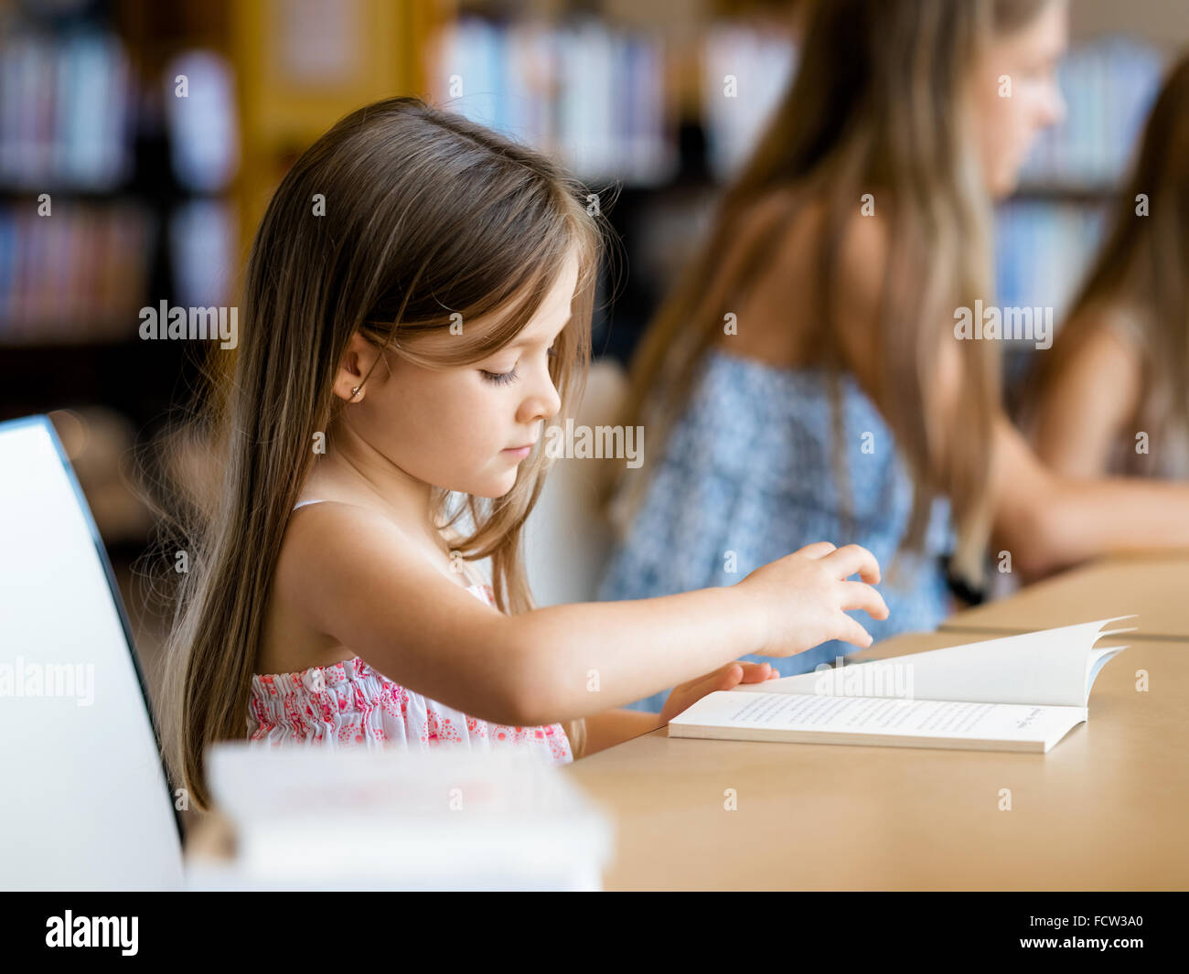 Little girls reading books in library Stock Photo - Alamy