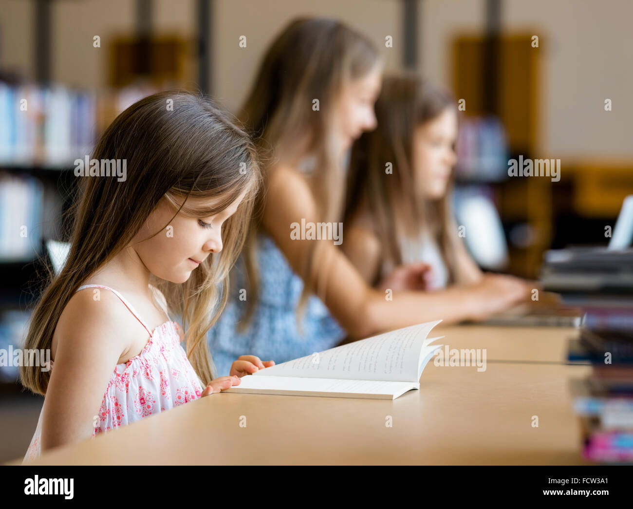 Little girls reading books in library Stock Photo - Alamy