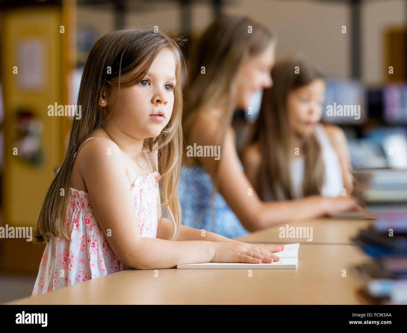 Little girls reading books in library Stock Photo - Alamy