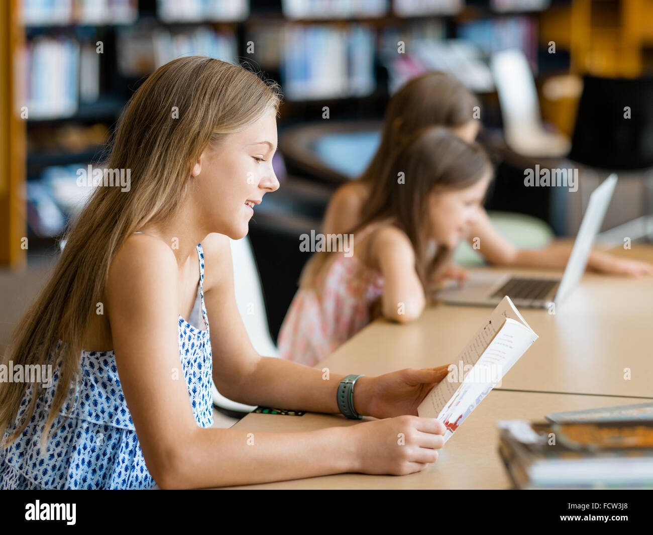 Little girls reading books in library Stock Photo - Alamy