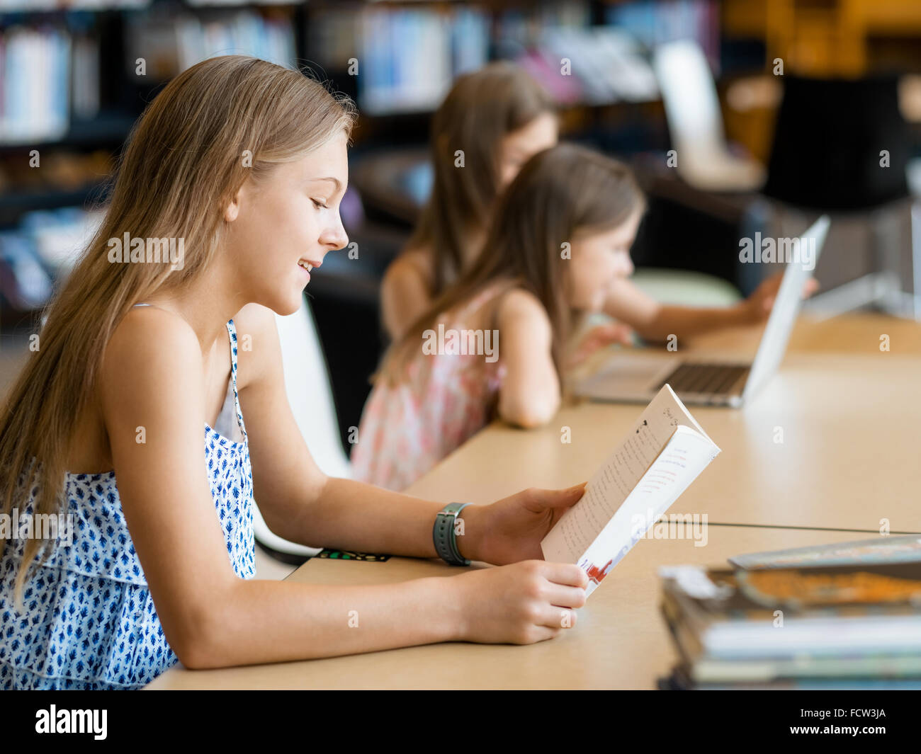 Little girl reading books in library Stock Photo - Alamy