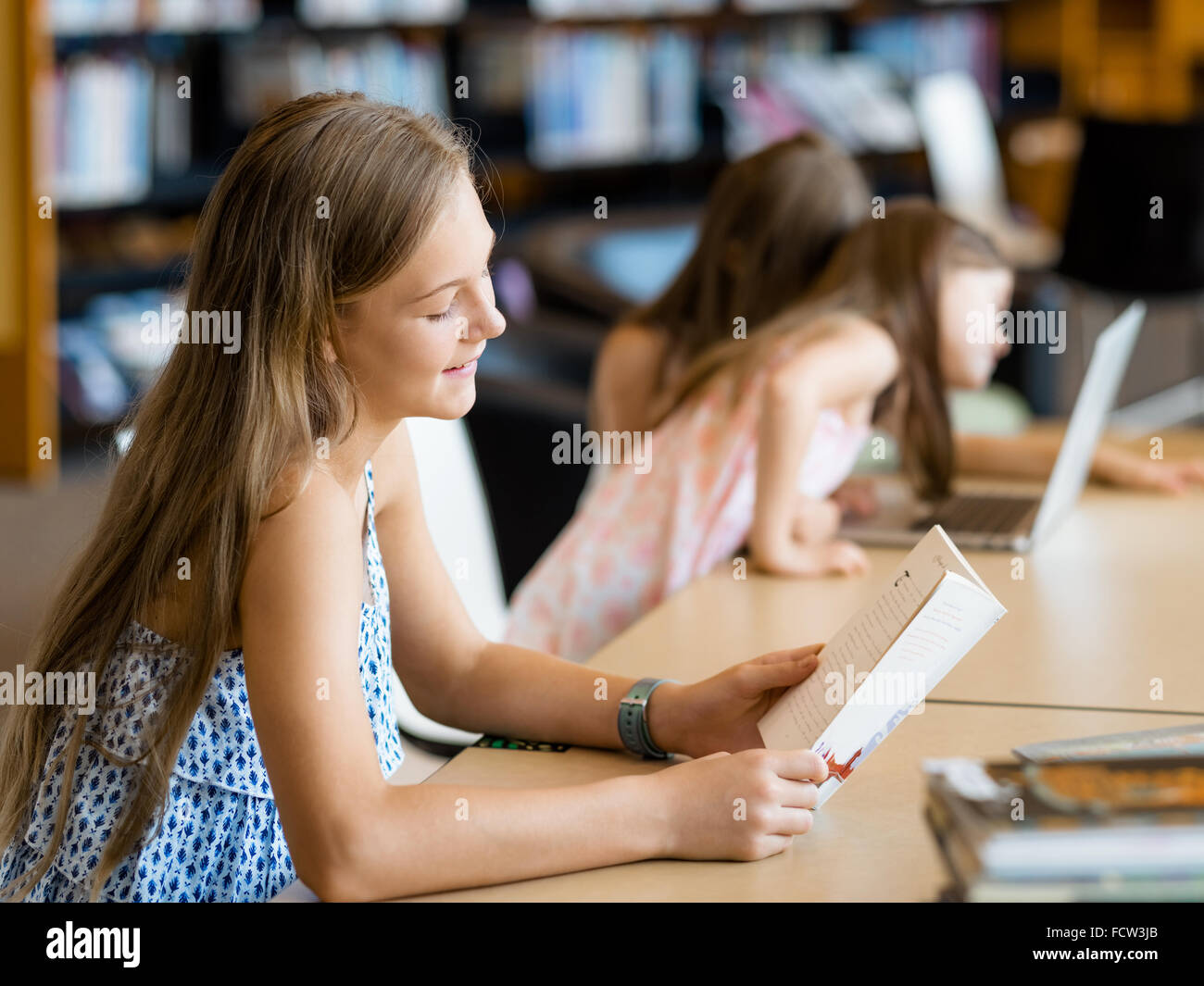 Little girl reading books in library Stock Photo - Alamy