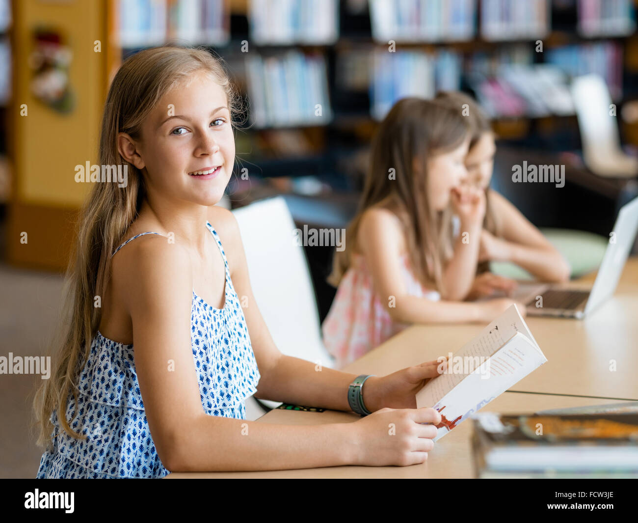 Little girl reading books in library Stock Photo - Alamy