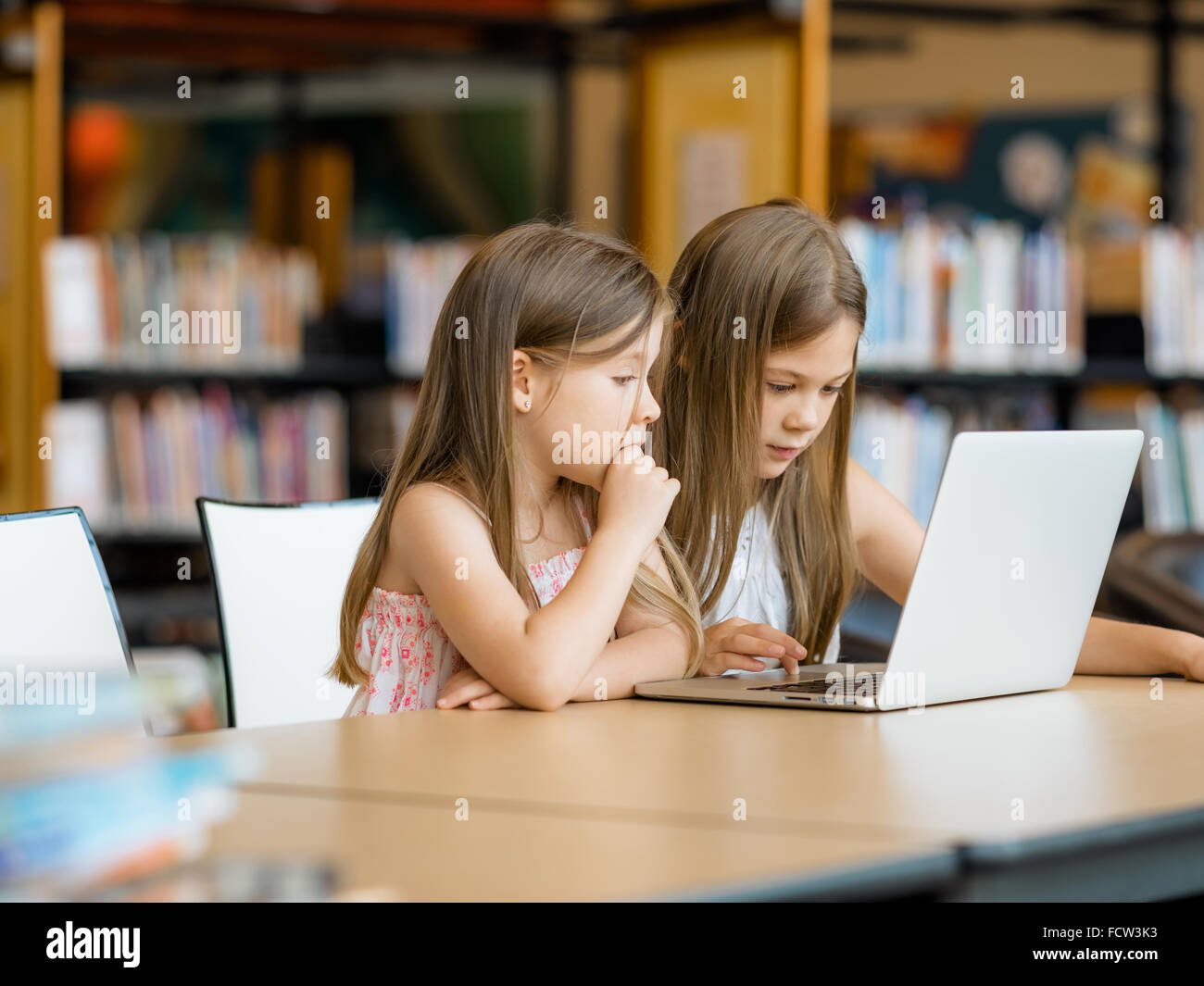 Little girls with a laptop in library Stock Photo - Alamy