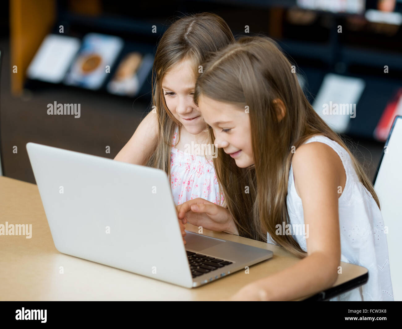 Little girls with a laptop in library Stock Photo - Alamy