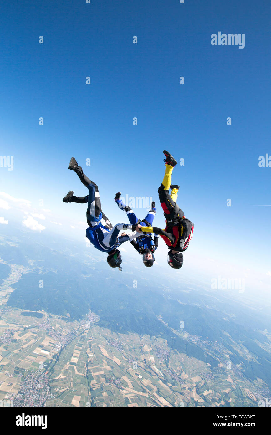 This freefly skydiving team is holding hand together in a head-down ...