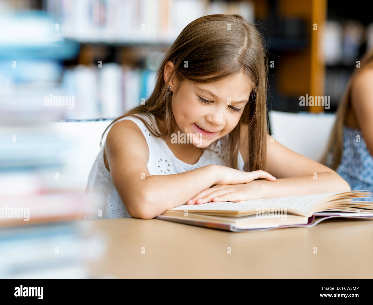 Little girl reading books in library Stock Photo - Alamy